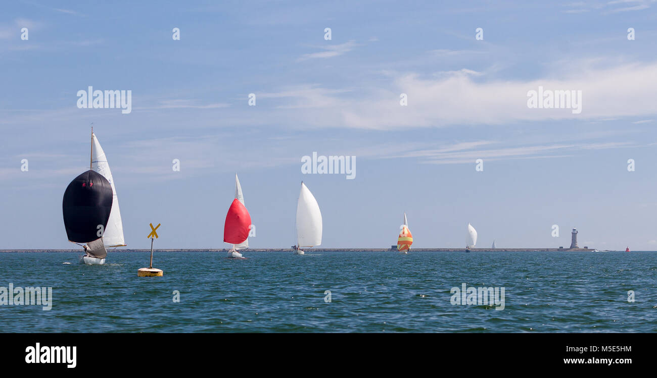 A fleet of classic racing yachts sail downwind under colourful ...