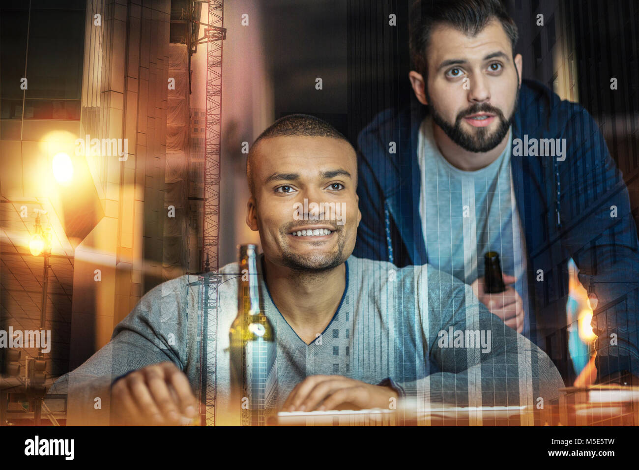 Interested man looking at the screen while his friend sitting and ...