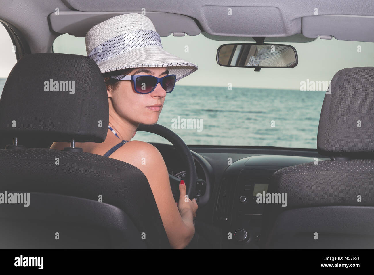 Portrait of fashionable young female in driver seat in car interior ...