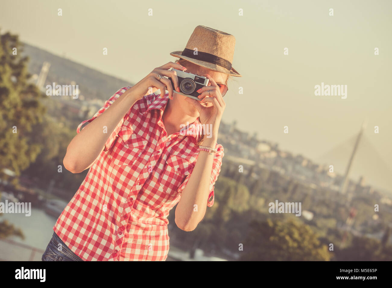 Portrait of young female taking photo with old retro camera outdoors ...