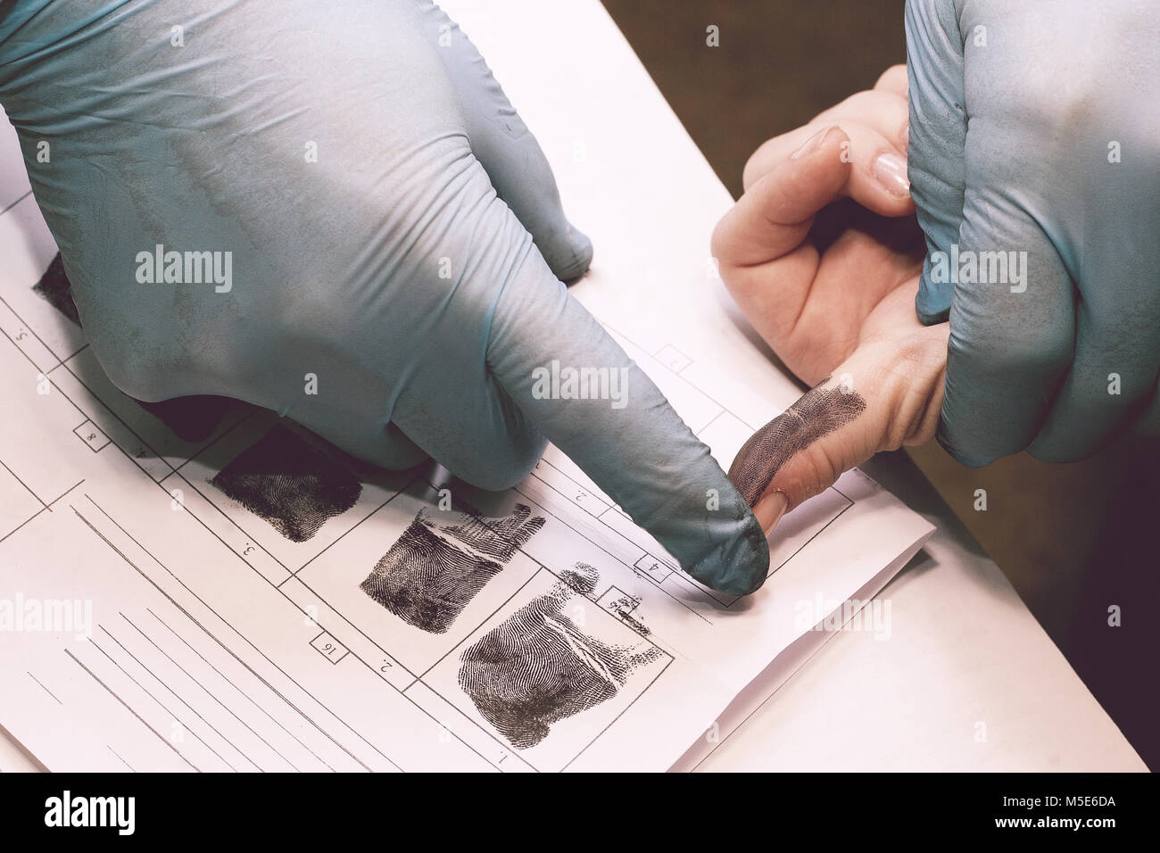 The investigator takes fingerprints from the suspect in the crime ...