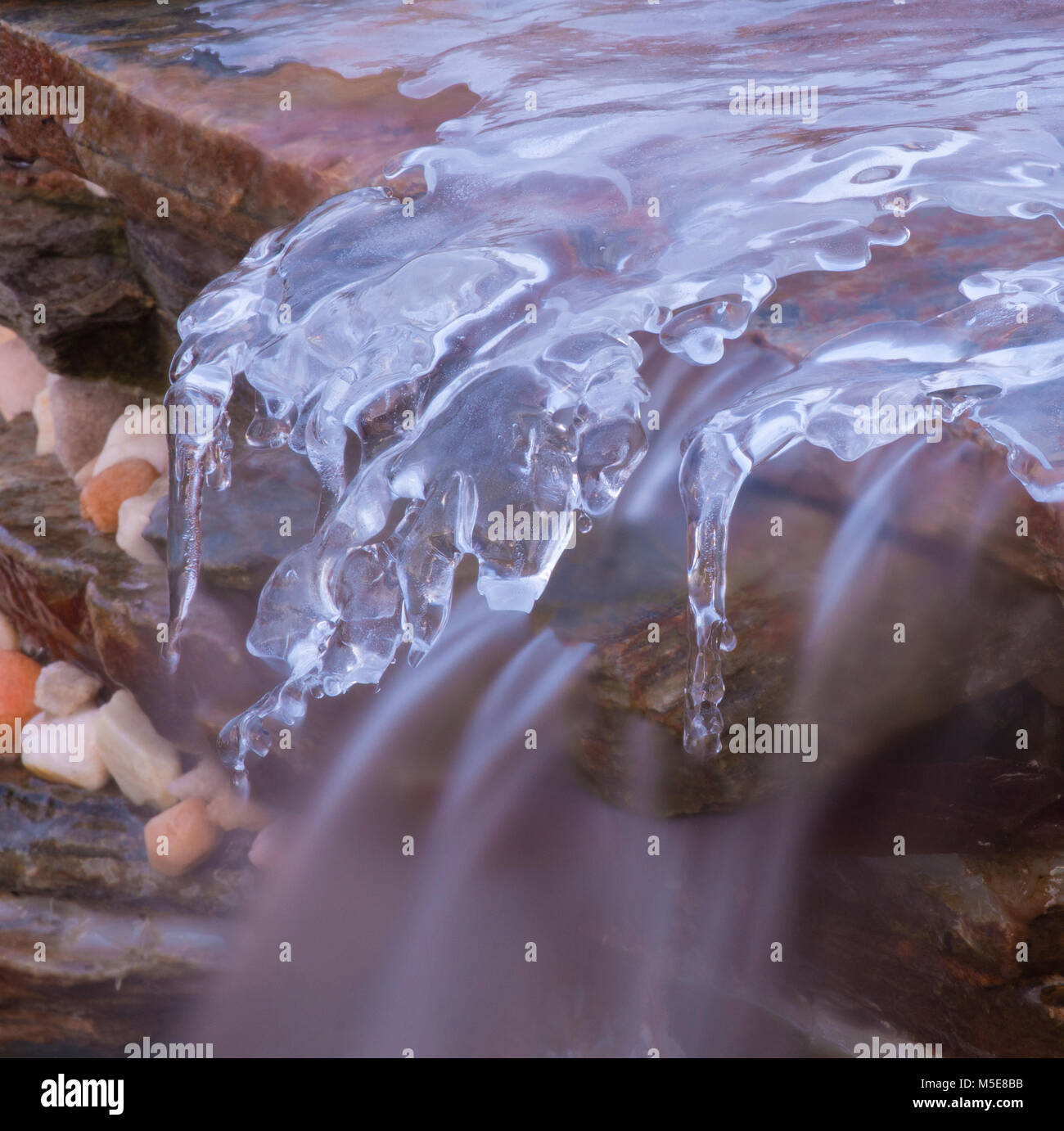 Small cascade with water flowing and icicles hanging Stock Photo - Alamy