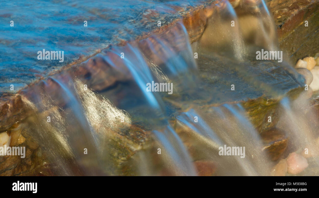 Small waterfall with water flowing over rocks in the sunlight Stock ...