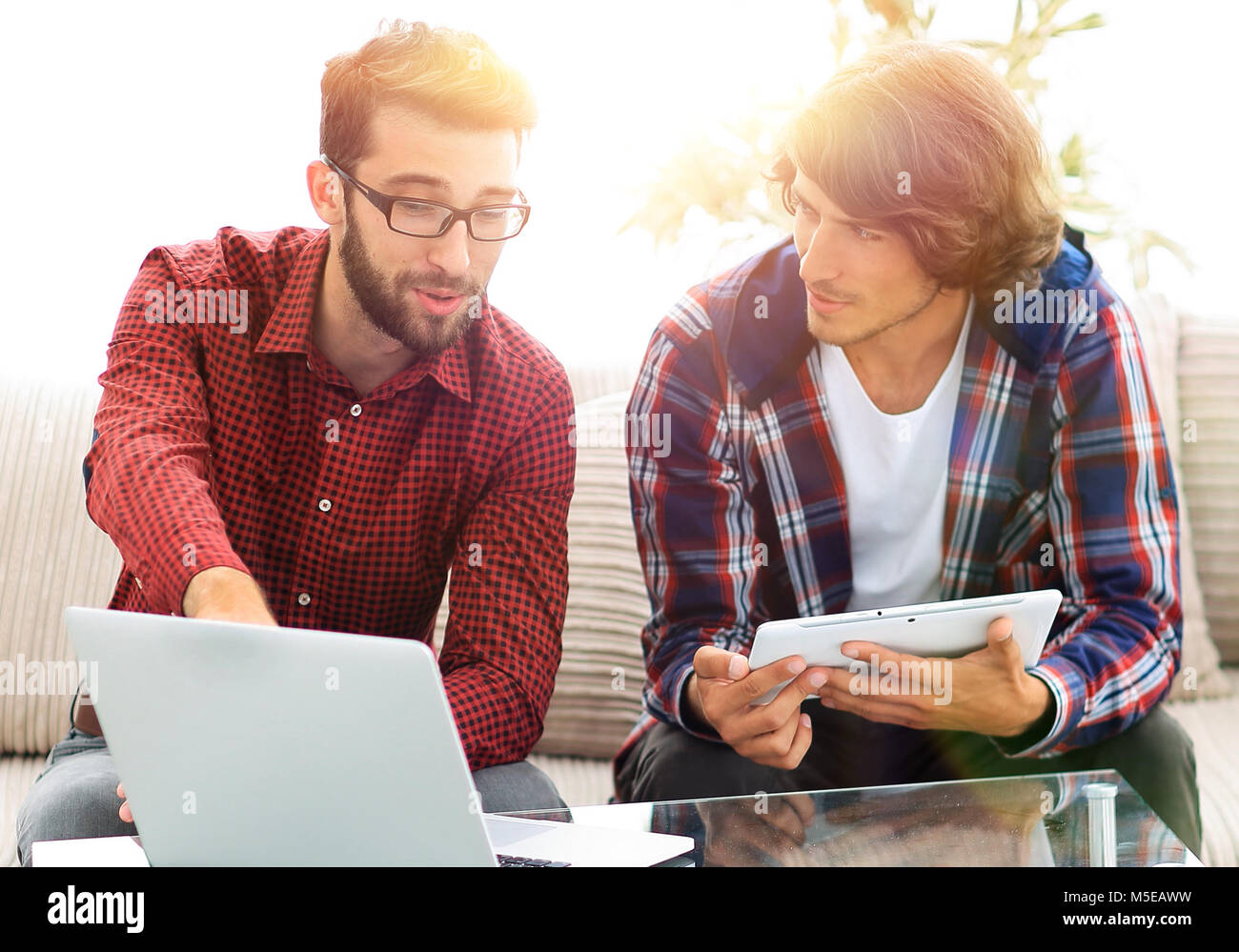 two young men working with laptop and tablet sitting on couch Stock ...