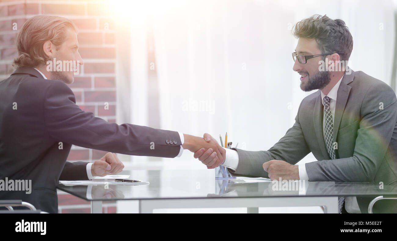 handshake of business partners sitting at their Desk Stock Photo - Alamy