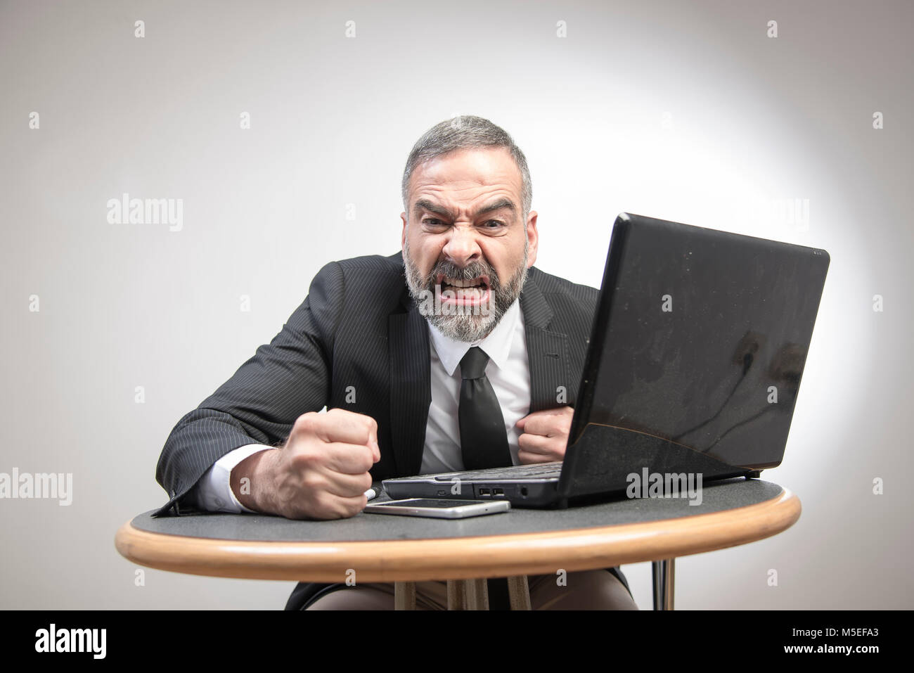 Senior business man shouting at his laptop, furious and frustrated with ...