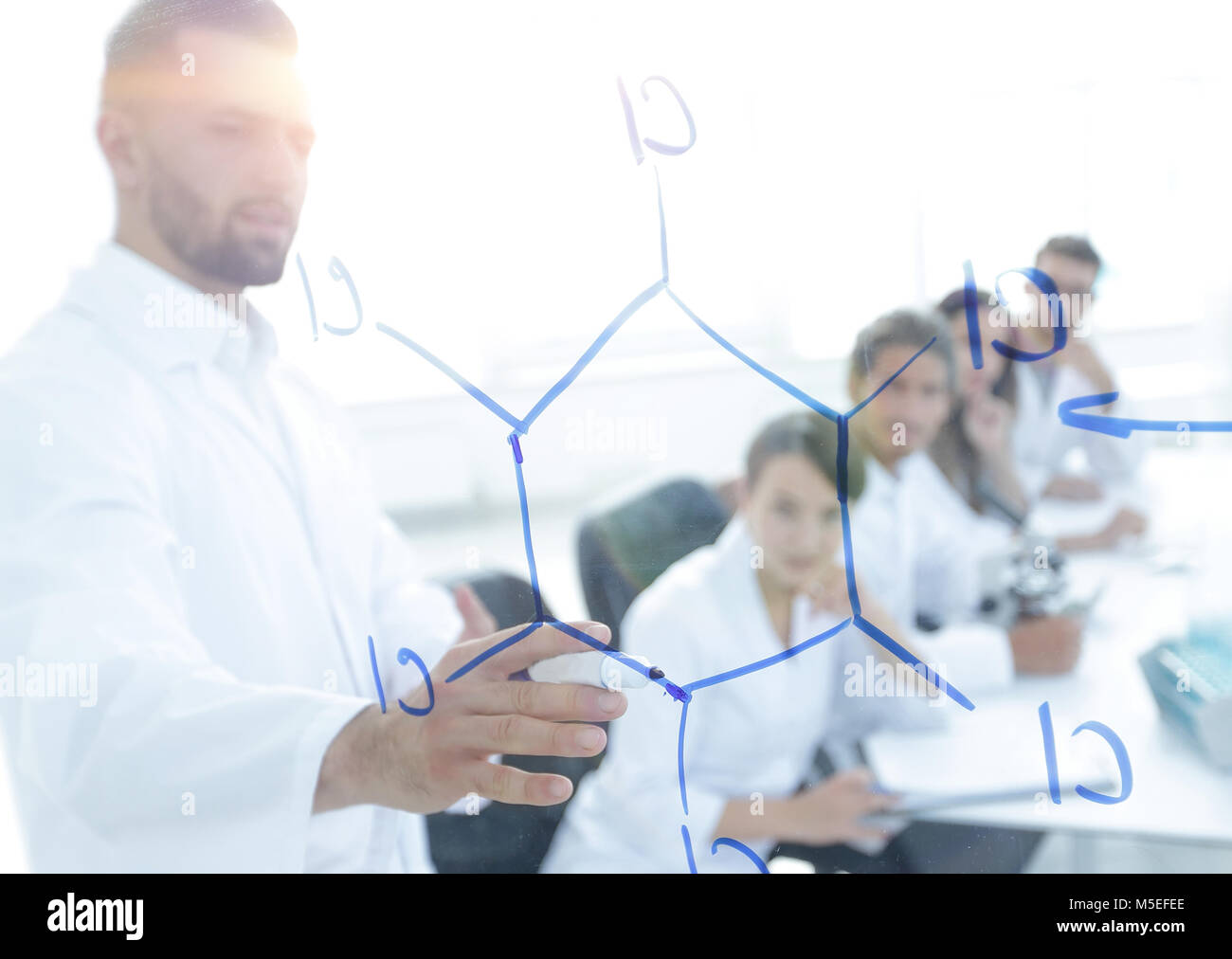 from behind the glass. a scientist standing near the blackboard Stock ...