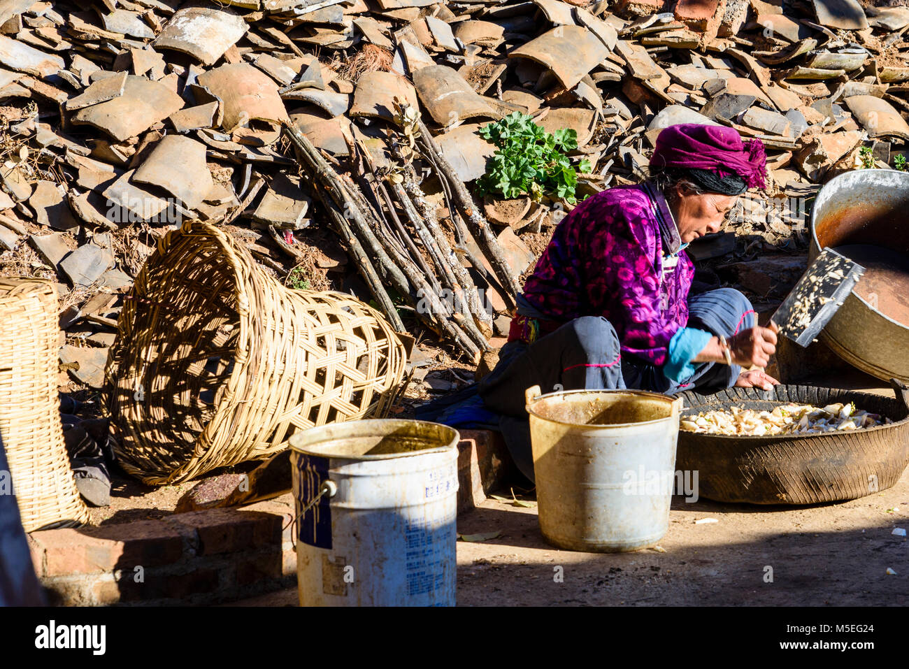 Mosuo minority lady preparing lunch for the family. Chopping food is an ...