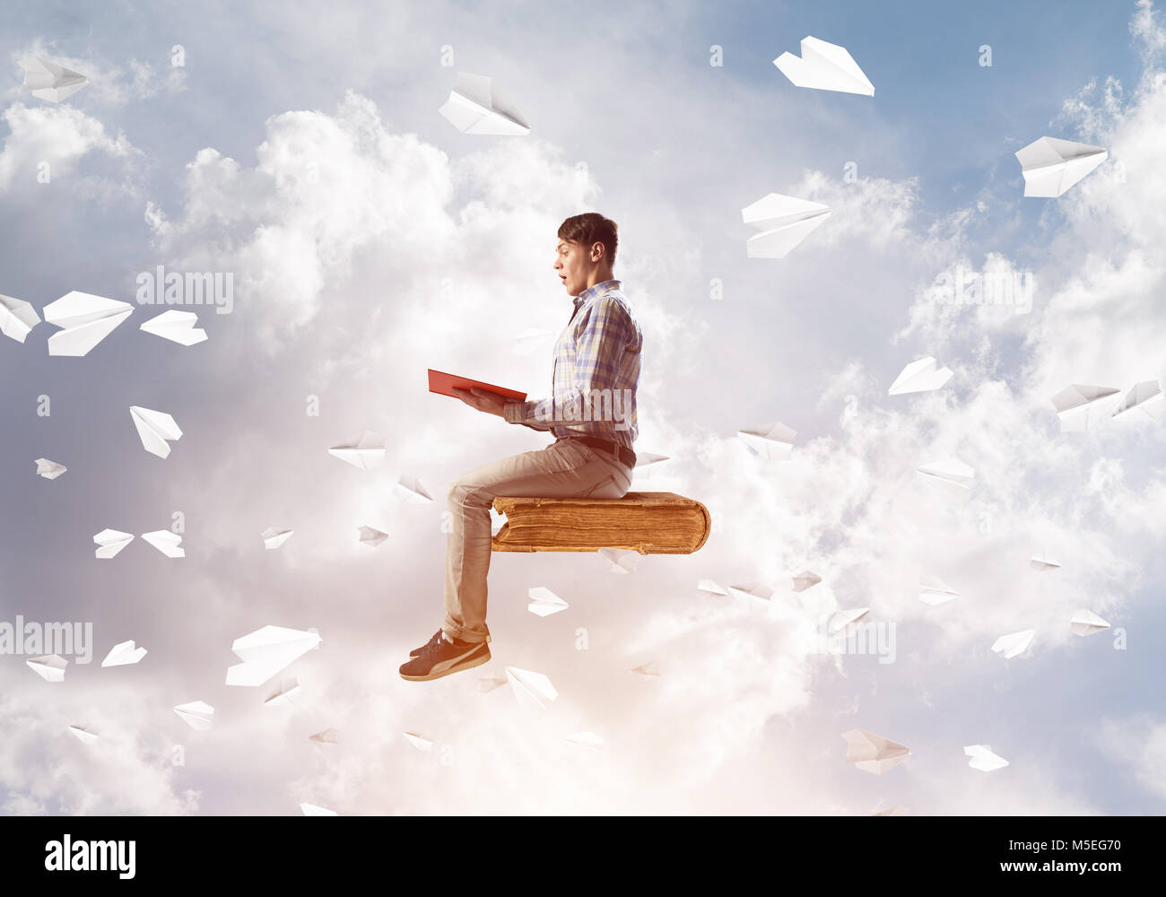 Handsome man student reading book and paper planes flying around Stock ...