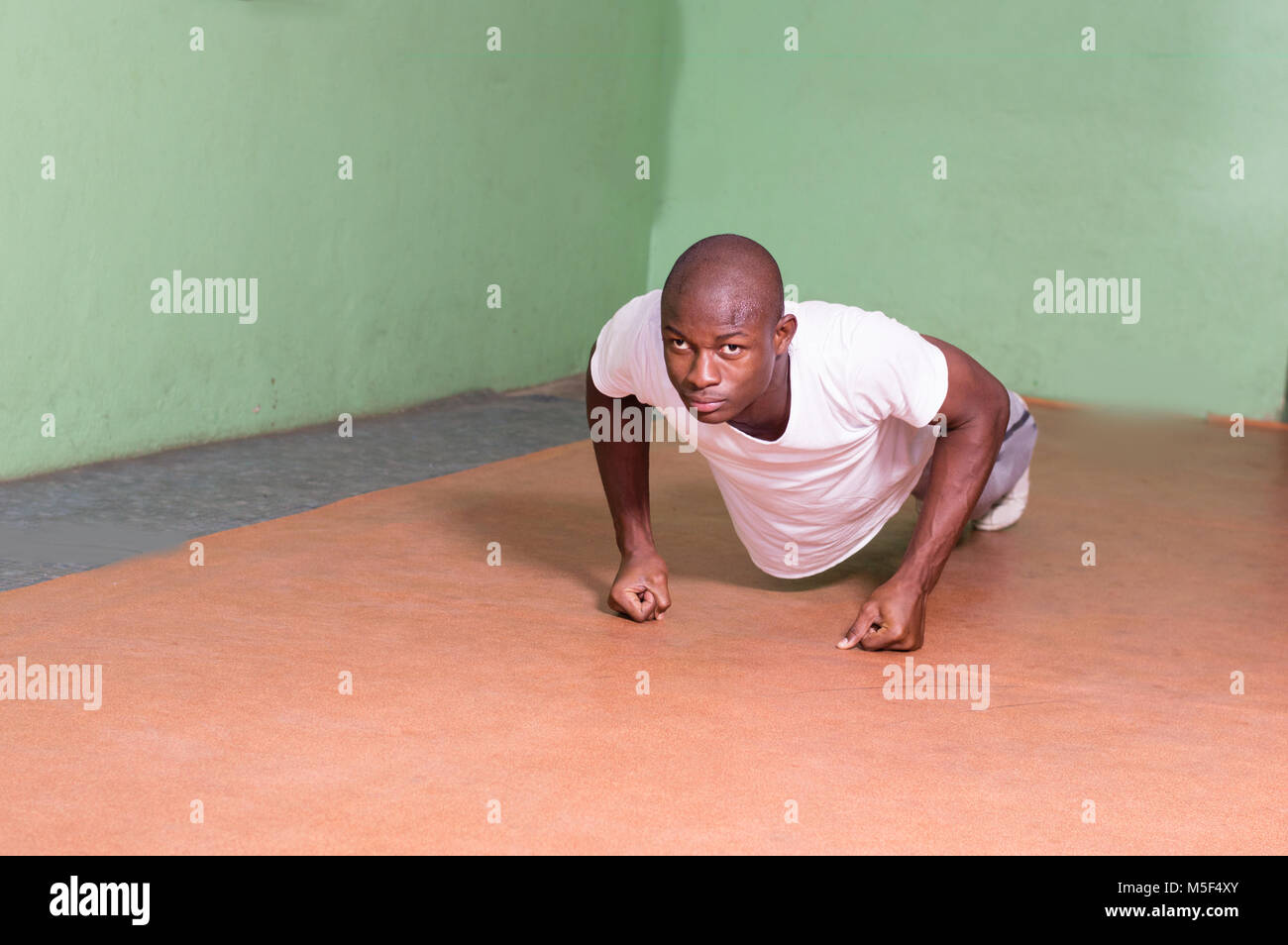 Young man making pumps on an orange carpet Stock Photo - Alamy