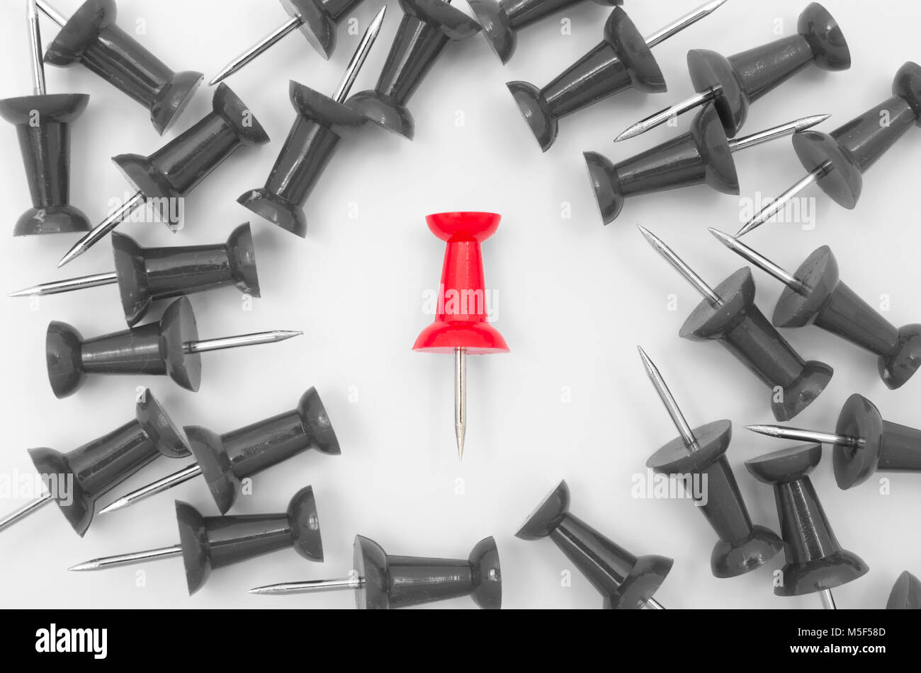 Single red plastic push pin surrounded by scattered gray push pins on ...