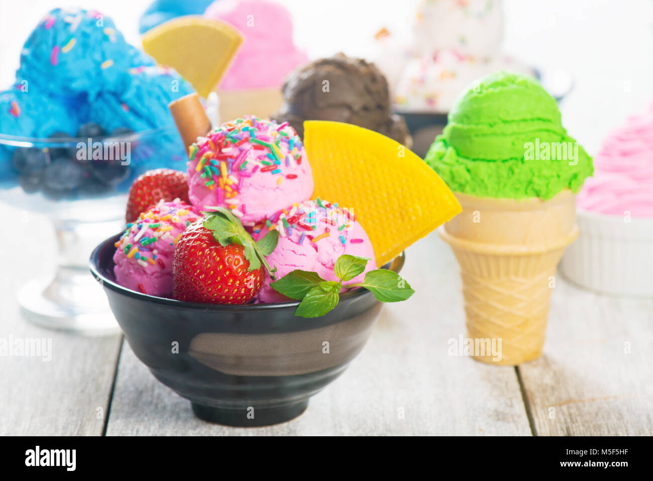 Different flavor ice cream in bowl on white rustic wooden background ...