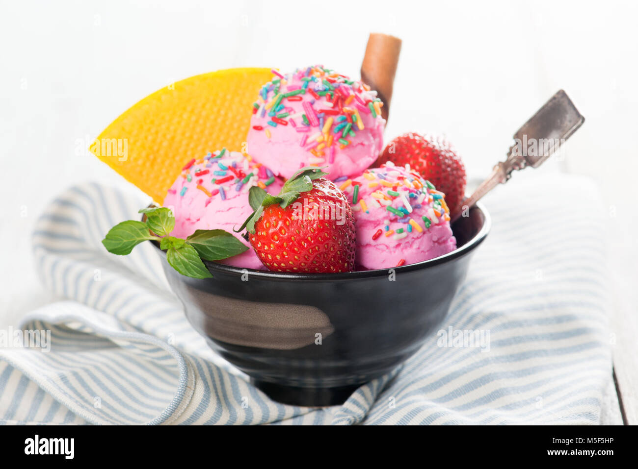 Pink ice cream in bowl with strawberry fruits and waffle on dining ...