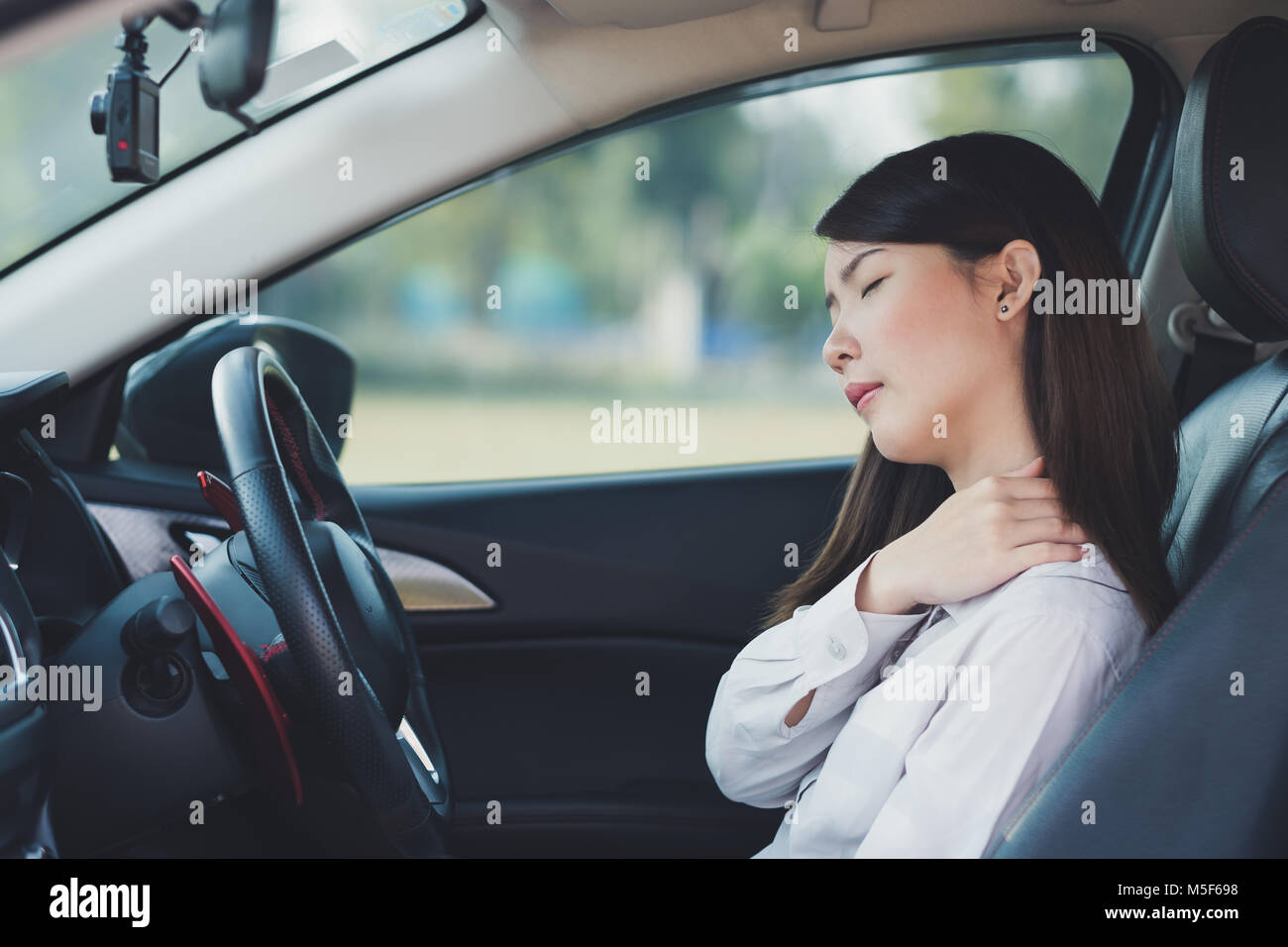 Asian businesswoman having pain on her shoulder and neck while driving ...