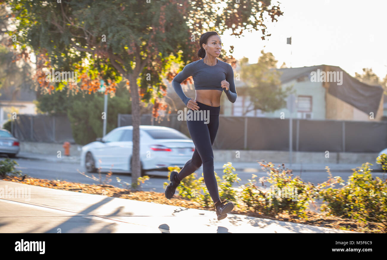Focused young dark-skinned female running in the golden sunlight Stock ...