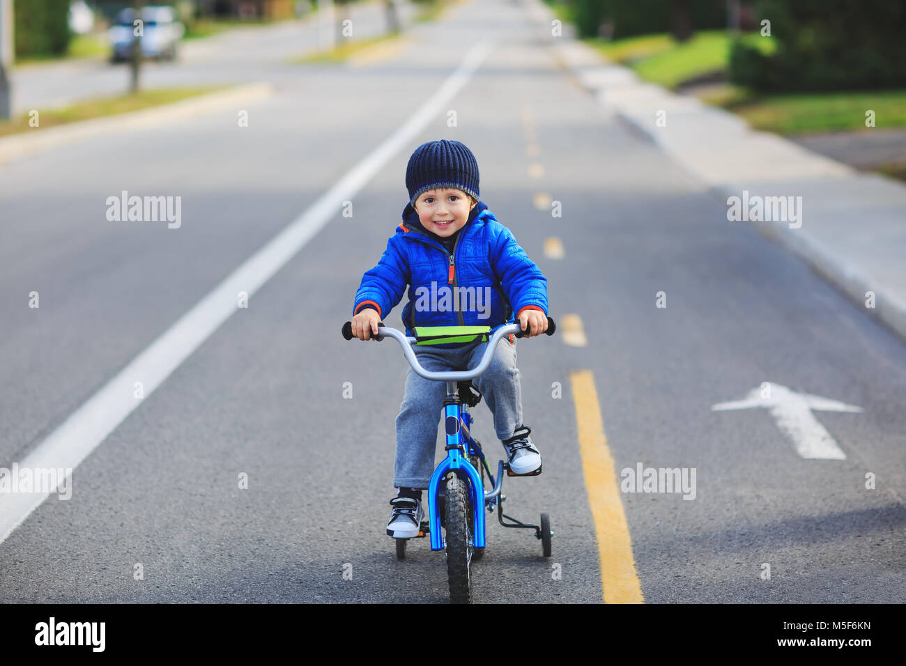 Happy child on a bicycle at asphalt road in spring or fall season. Cute ...