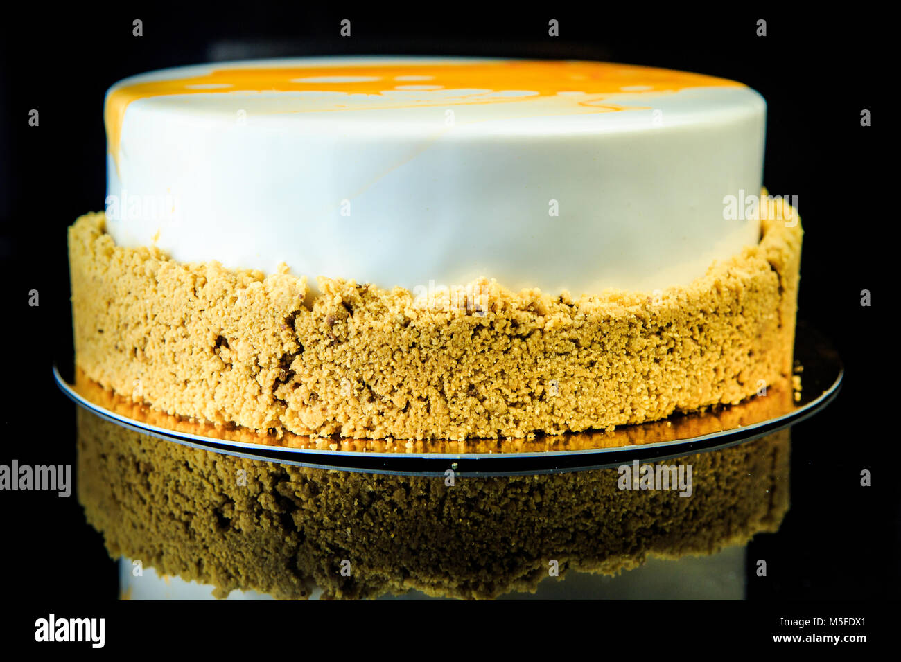 bright white musk cake coated with white and yellow glaze on black ...