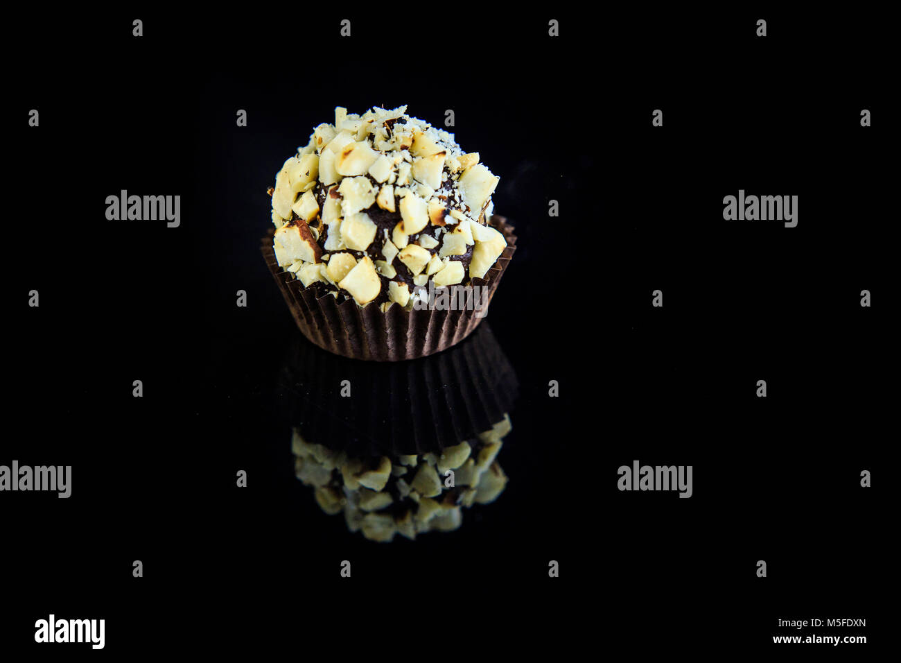 round-balled small chocolate candy on black mirror background with ...
