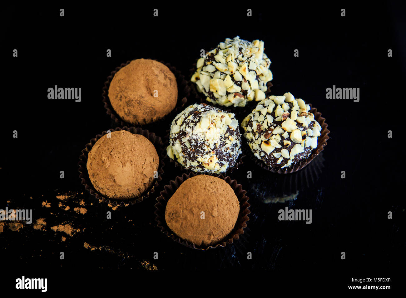 set of round-balled small chocolate candies on black mirror background ...