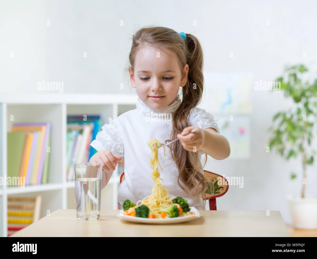 Kid little girl eats vegetarian food at home or kindergarten Stock ...