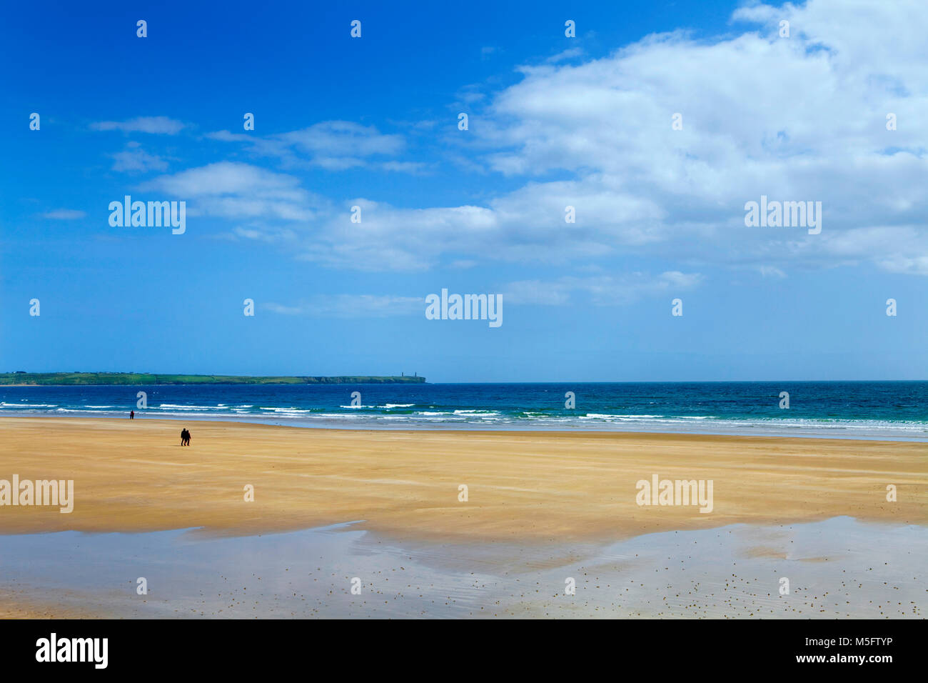 Walkers on the strand in Tramore with Brownstown Head in the background ...