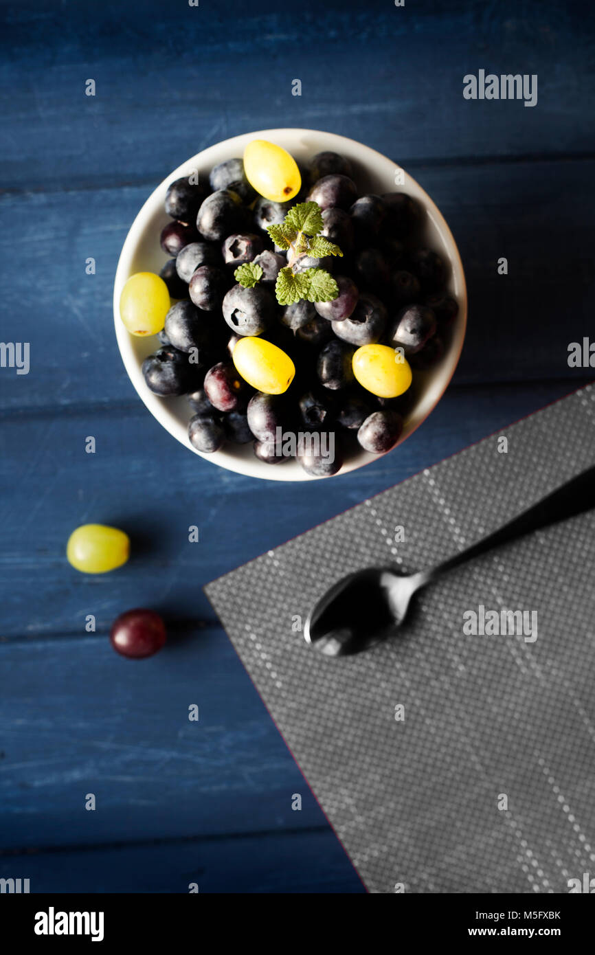 Vibrant image of two fruits; blueberries and grapes on wooden base with ...