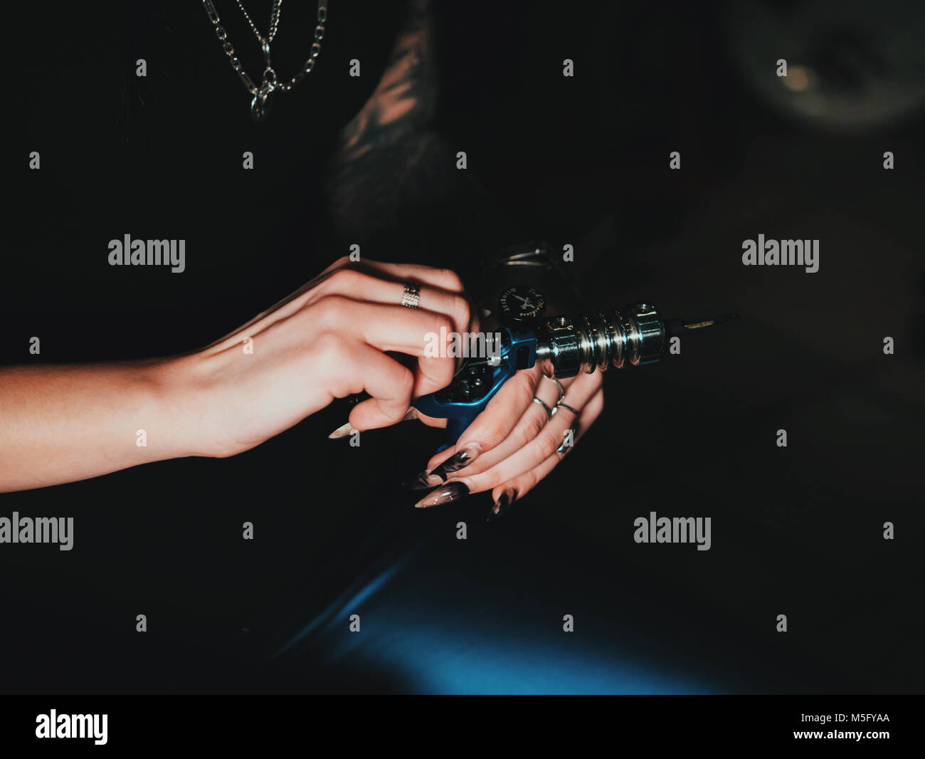 Artist prepares tools and machine for tattoo session, woman holding a ...