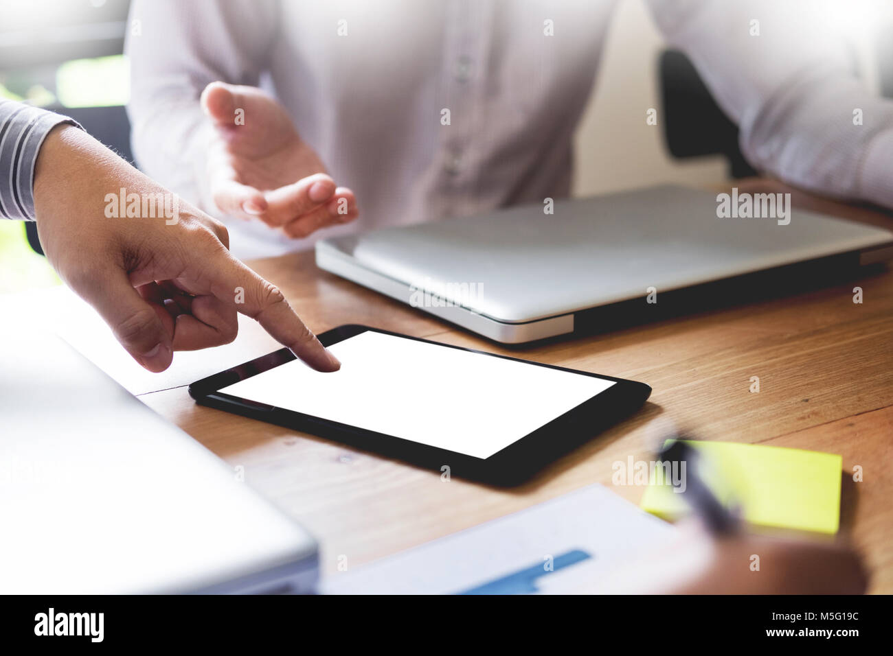 Two young businessmen using touchpad explaining his business plans to ...