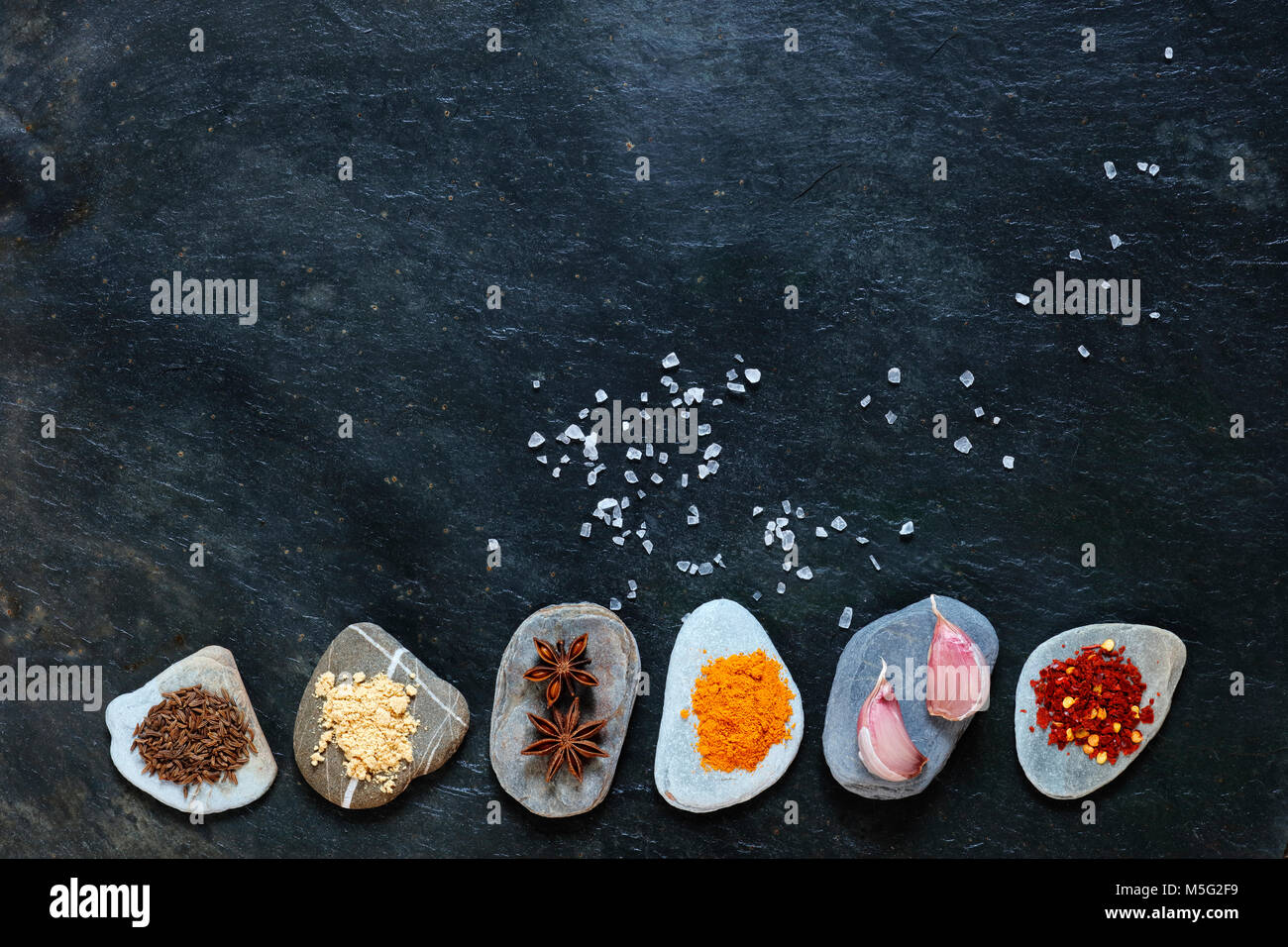Colorful spices on pebbles with rock salt with copy space above Stock ...