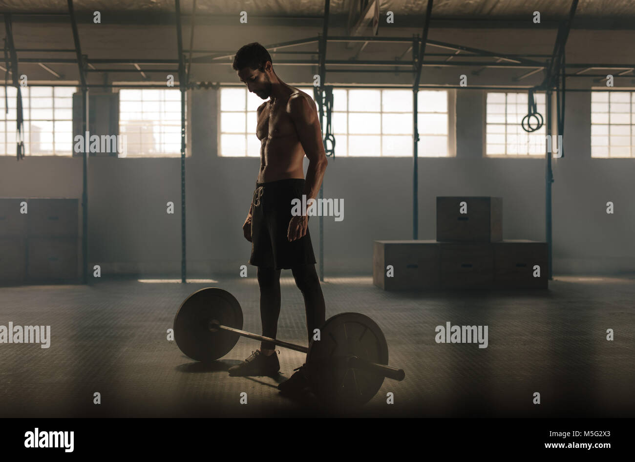 Man exercising with barbell at gym. Man standing with heavy weights ...
