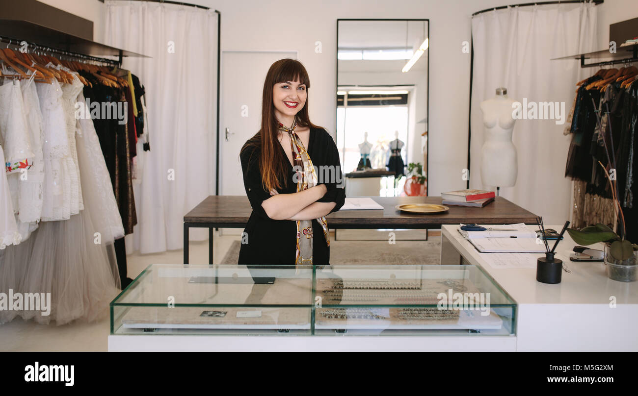 Female fashion designer standing at her desk in her boutique. Female ...