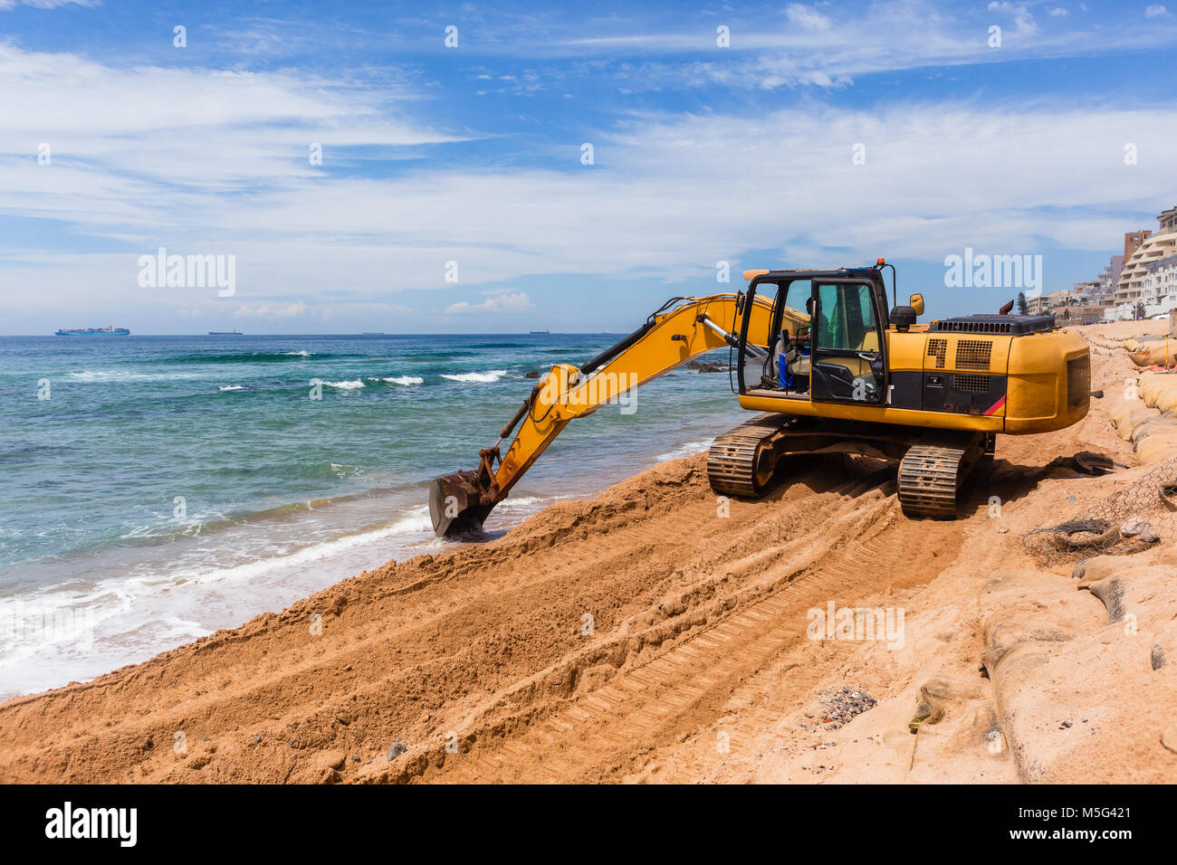 Construction excavators machines on beach water line coastline building ...