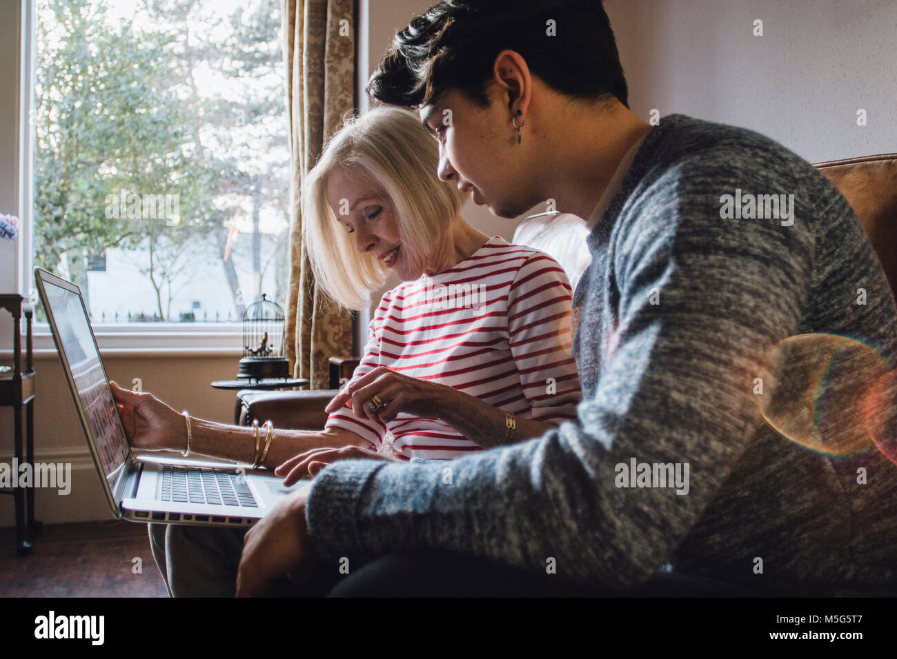 Teenage boy is showing his grandmother how to use a laptop Stock Photo ...