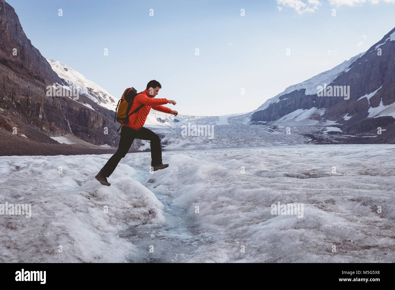 Man jumping over stream during winter Stock Photo - Alamy