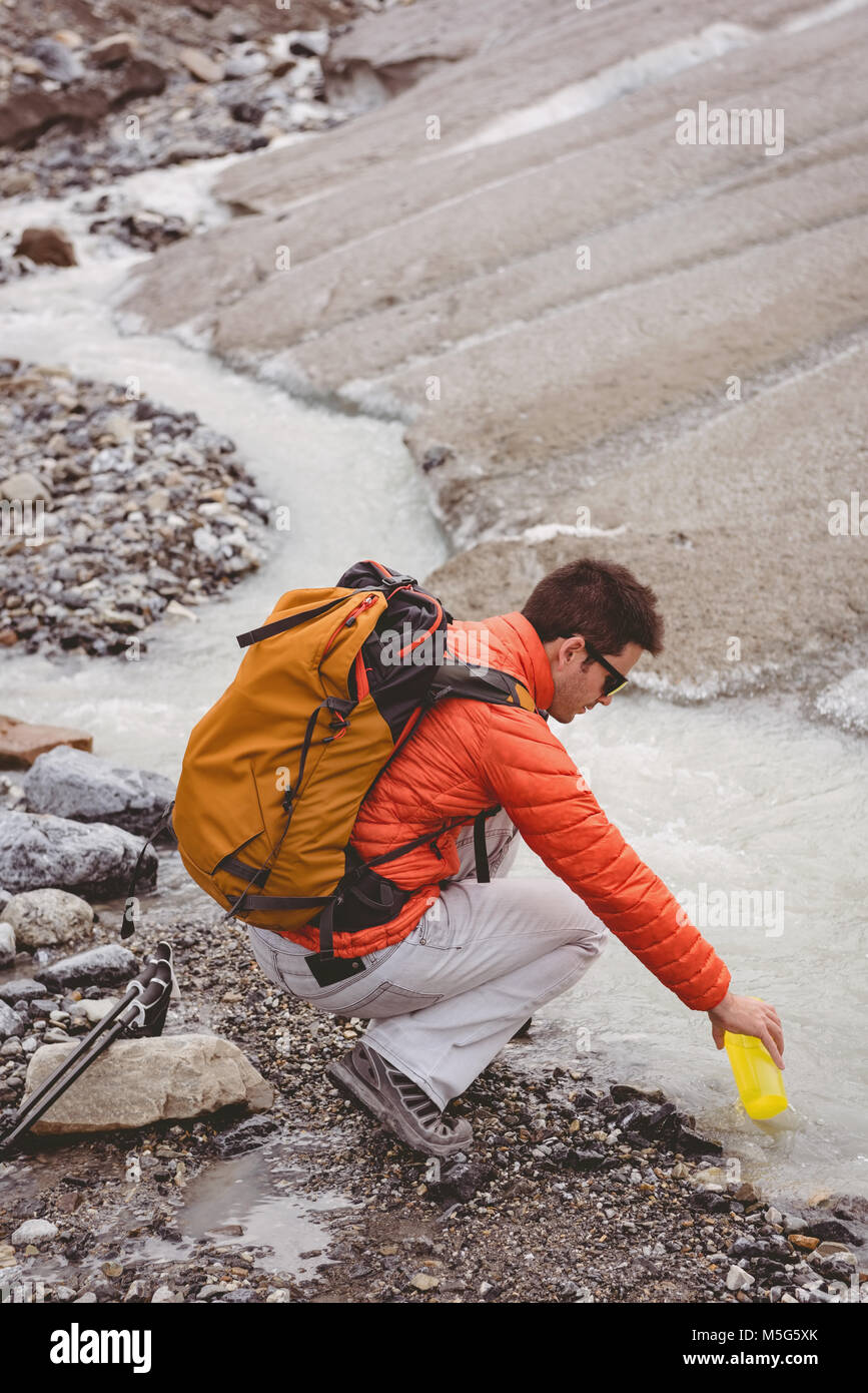 Male hiker filling water in bottle from stream Stock Photo - Alamy