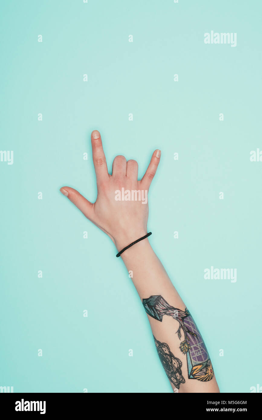 cropped shot of woman showing horns sign isolated on turquoise Stock ...