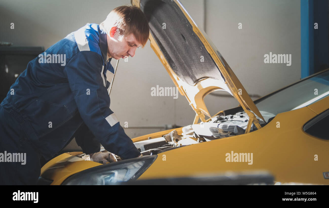 Mechanic in car workshop - repairing in engine compartment Stock Photo ...
