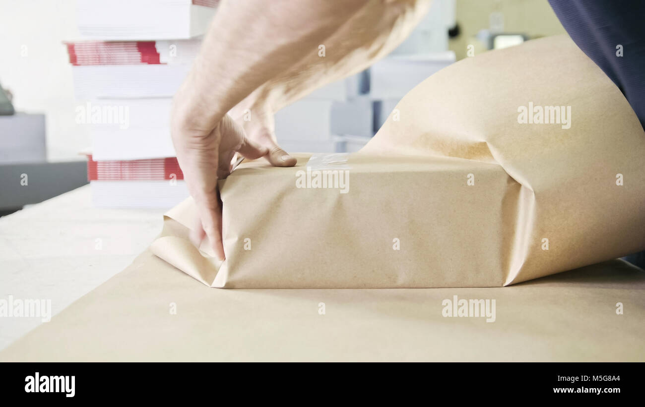 Close up man's hands packing boxes of sellotape in printing industry ...