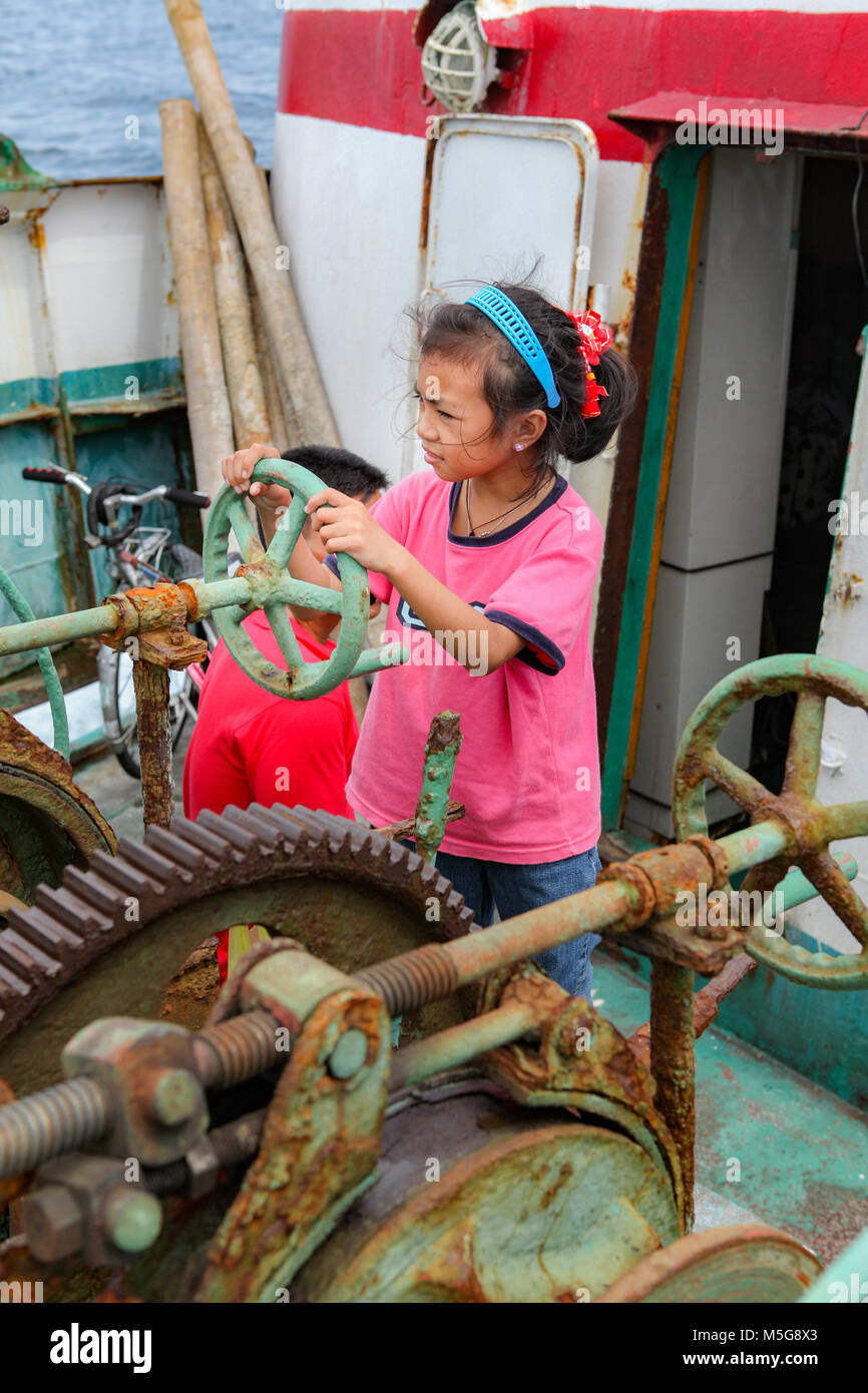 A four-year old Filipino girl plays driving the ship with old machinery ...