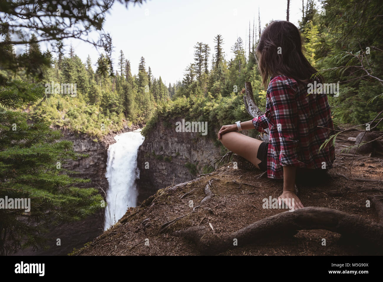 Woman sitting near waterfall Stock Photo - Alamy