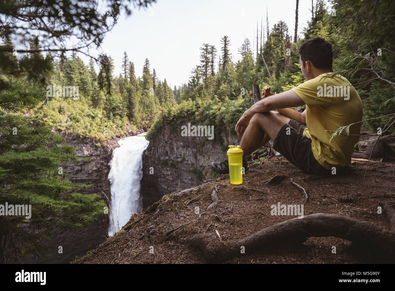Man sitting near waterfall Stock Photo - Alamy