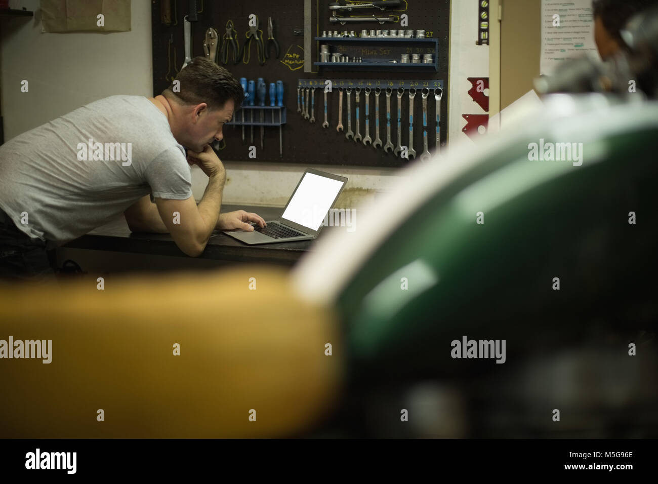 Mechanic using laptop in garage Stock Photo - Alamy
