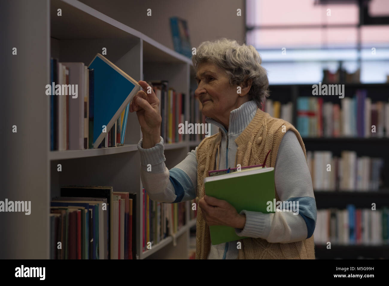 Woman removing book from shelf hi-res stock photography and images - Alamy