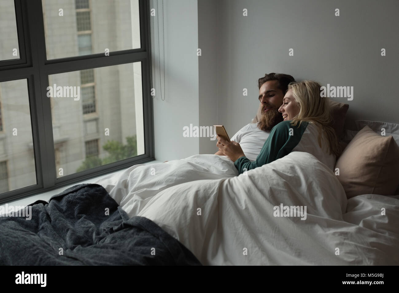 Couple using mobile phone in bedroom Stock Photo - Alamy