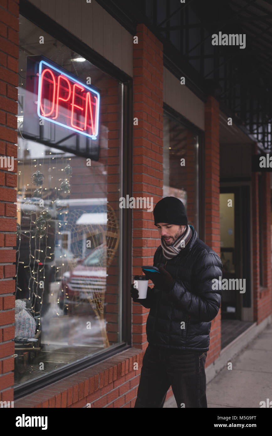 Man using mobile phone outside the shop Stock Photo - Alamy