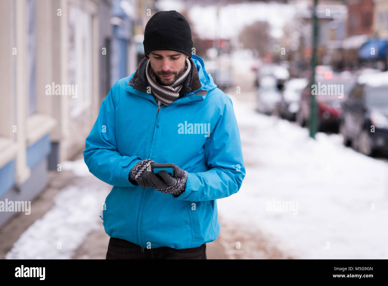 Man using mobile phone while walking on sidewalk Stock Photo - Alamy