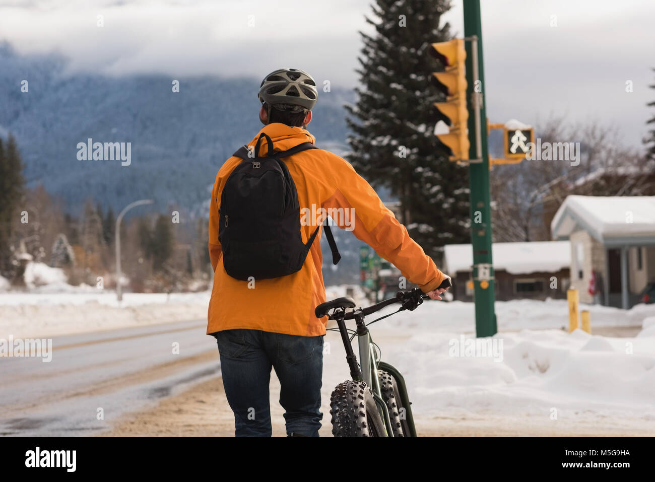 Man walking with his cycle on sidewalk during winter Stock Photo - Alamy