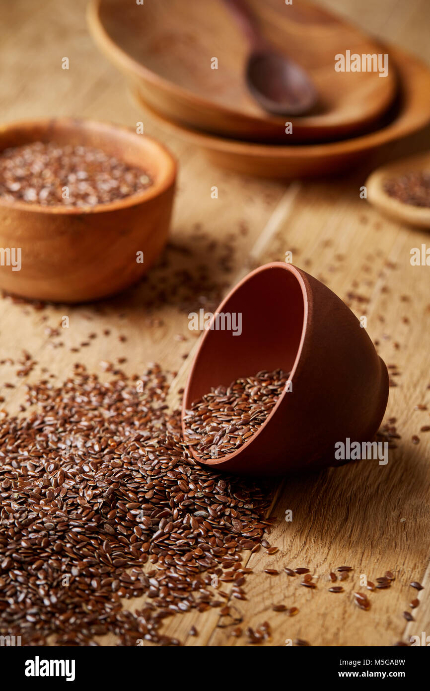 An overturned ceramic clay bowl with linseeds on a brown rustic wooden ...