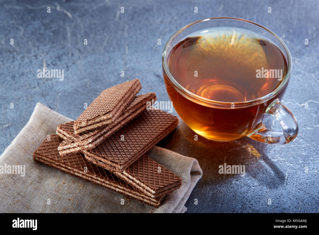 A transparent glass cup of black tea with tasty chocolate waffles on ...