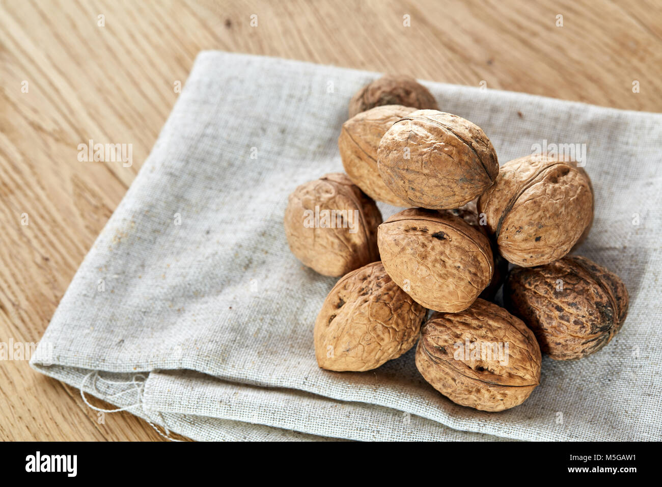 A stack of hard shells of walnuts piled together on light grey fabric ...
